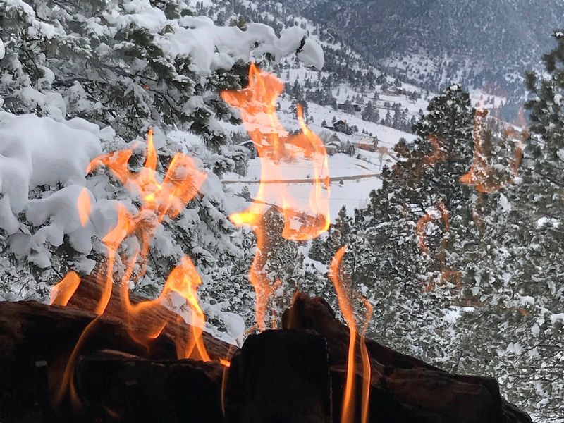 looking at snow on the mountains through a fire in the fireplace ...