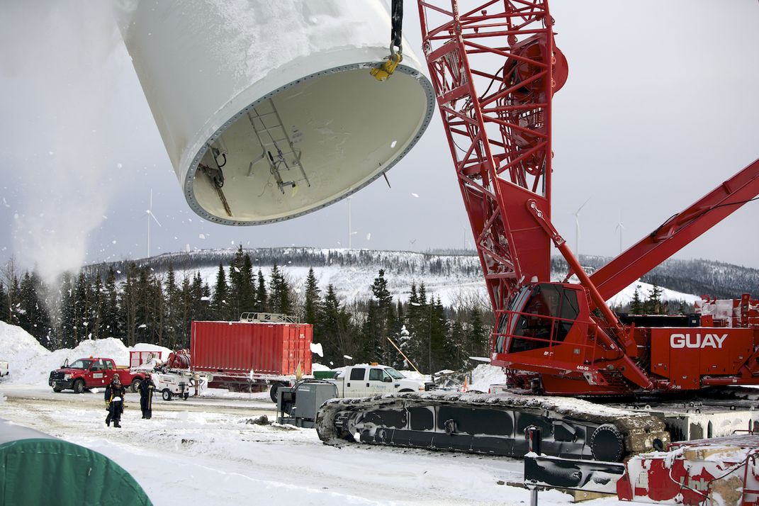 Snow falls from the mid-section of a wind tower as it is lifted by a ...
