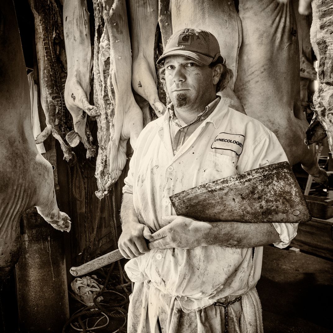 Man with cleaver in the barn with the hog harvest | Smithsonian Photo ...