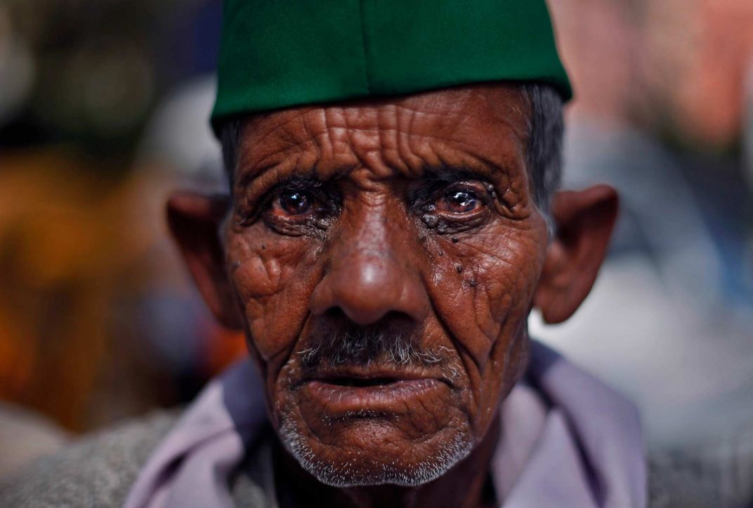 An elderly Indian farmer listens to a speaker, unseen, during a protest ...