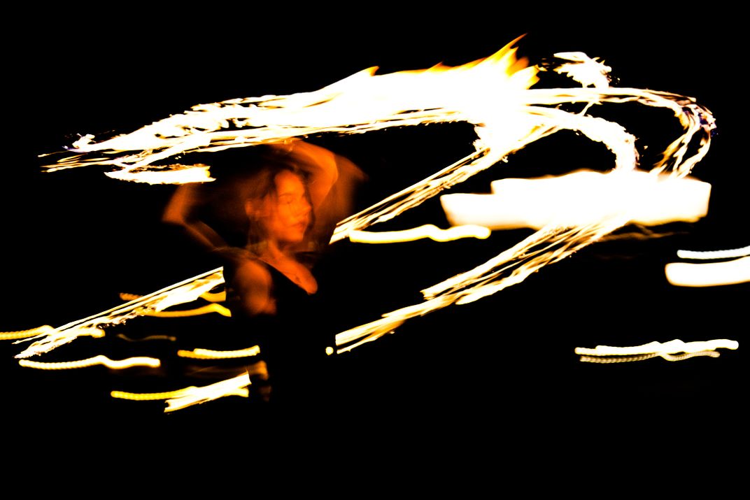 A young pyrotechnicien loses herself in spinning flames outside of the ...