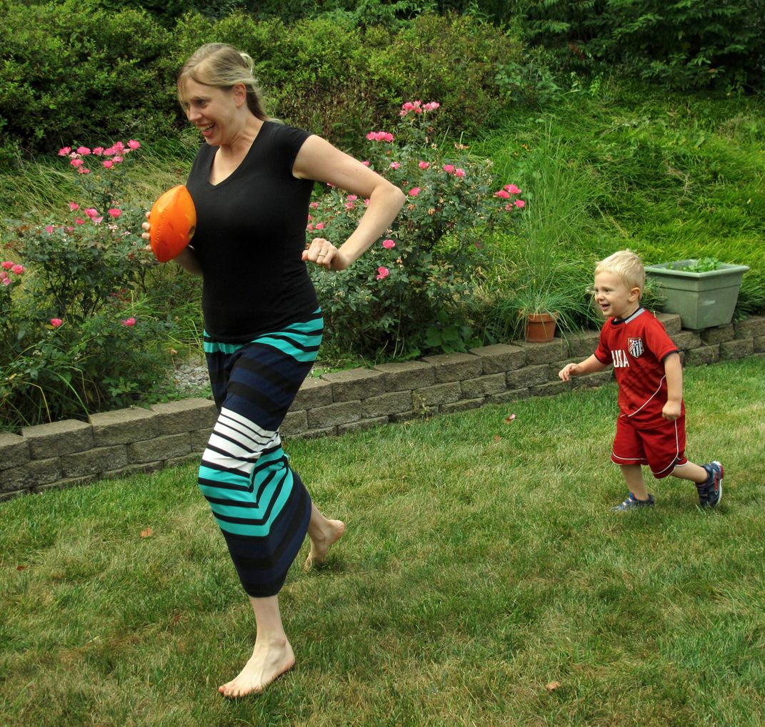 A toddler plays football in the backyard with mom. | Smithsonian Photo ...