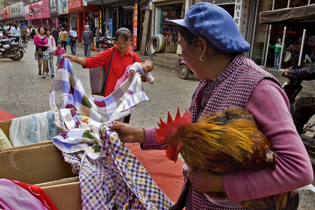 Two women selecting clothes at a market in the small town in Huize in ...