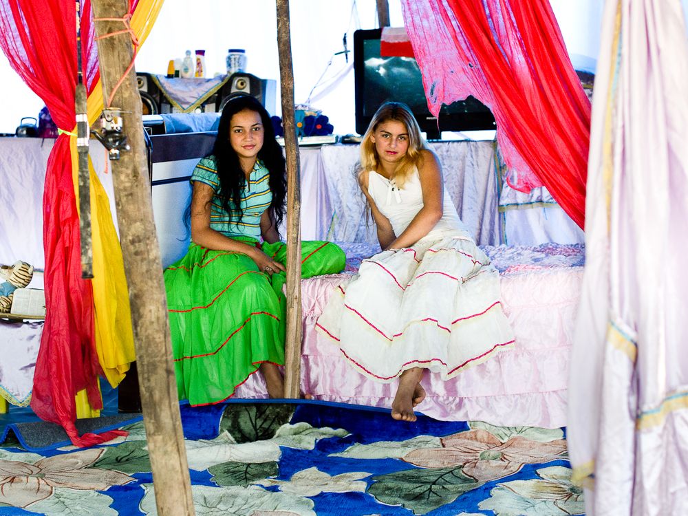 Two Brazilians gypsies are inside a tent, sited on the bed, wearing ...