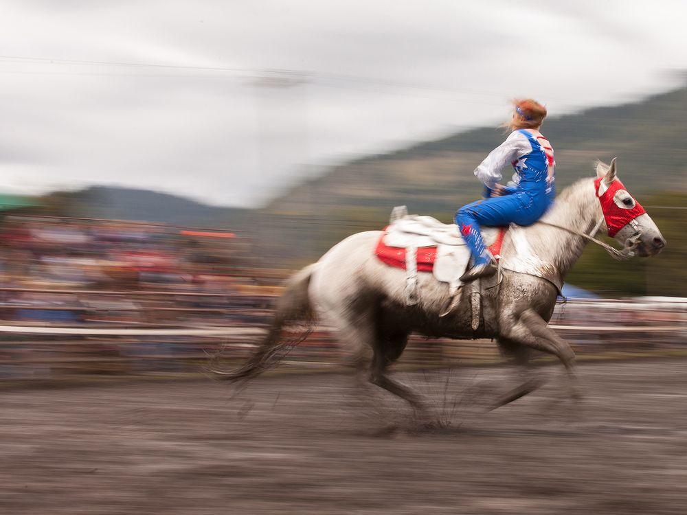 Female stunt rider going backwards on a horse in the mud at a local ...