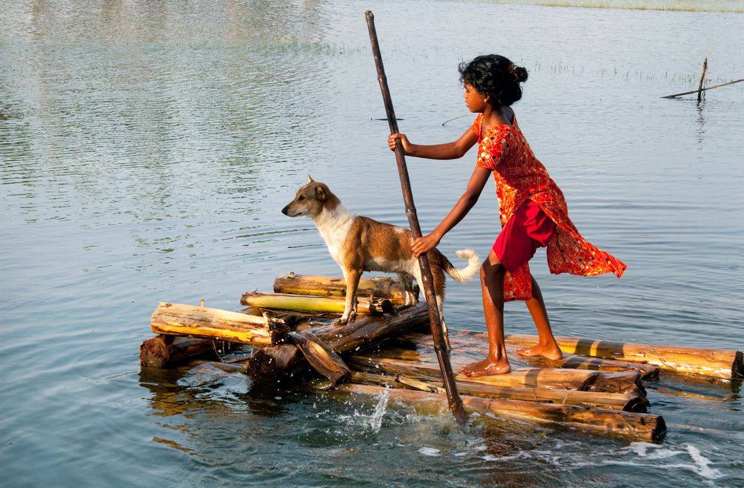 A girl carries her pet by a banana raft aftermath of a devastating ...