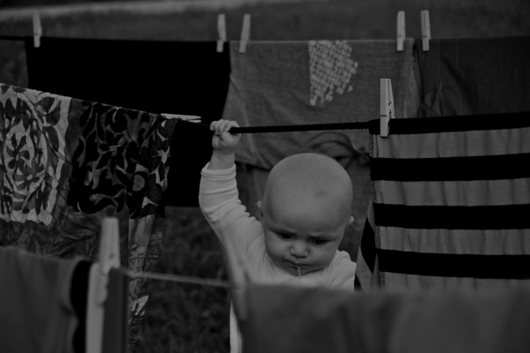 a baby hanging from a rope,like he is doing laundry himself ...
