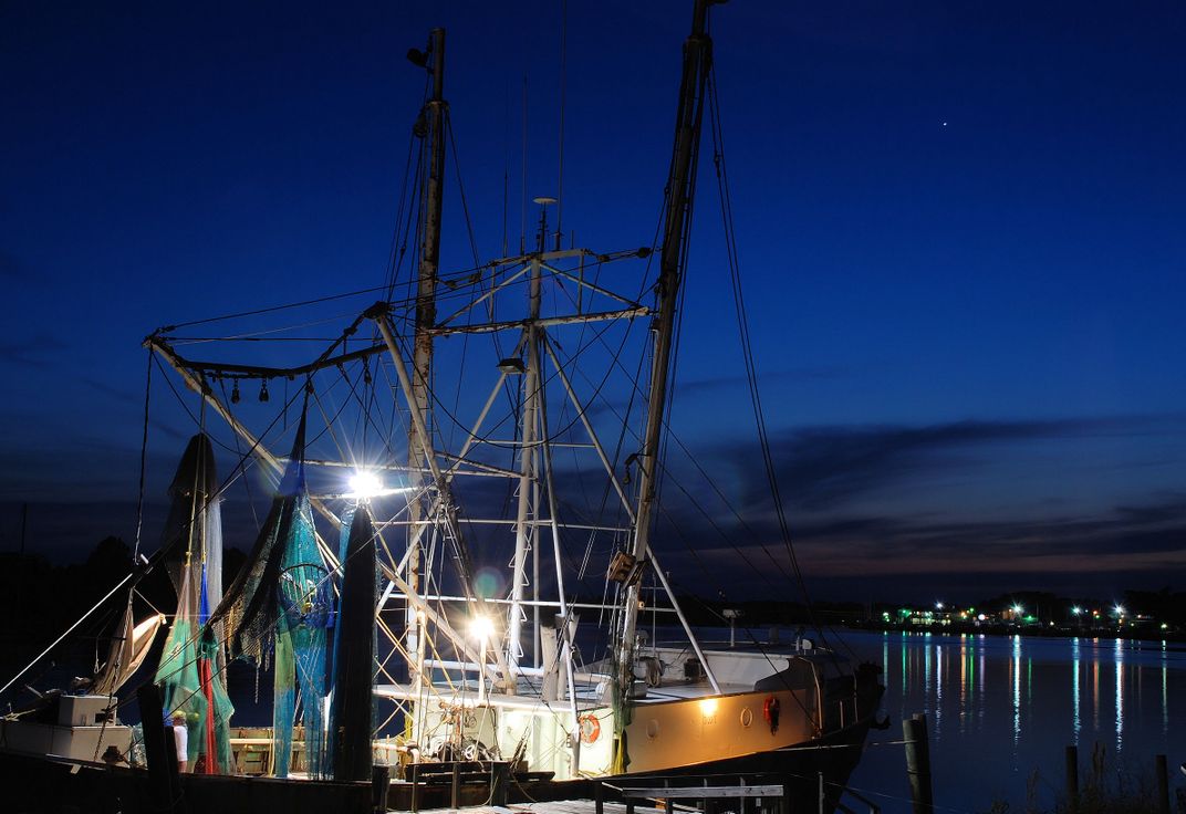 A fishing vessel captain tends to his nets at the end of the day in ...