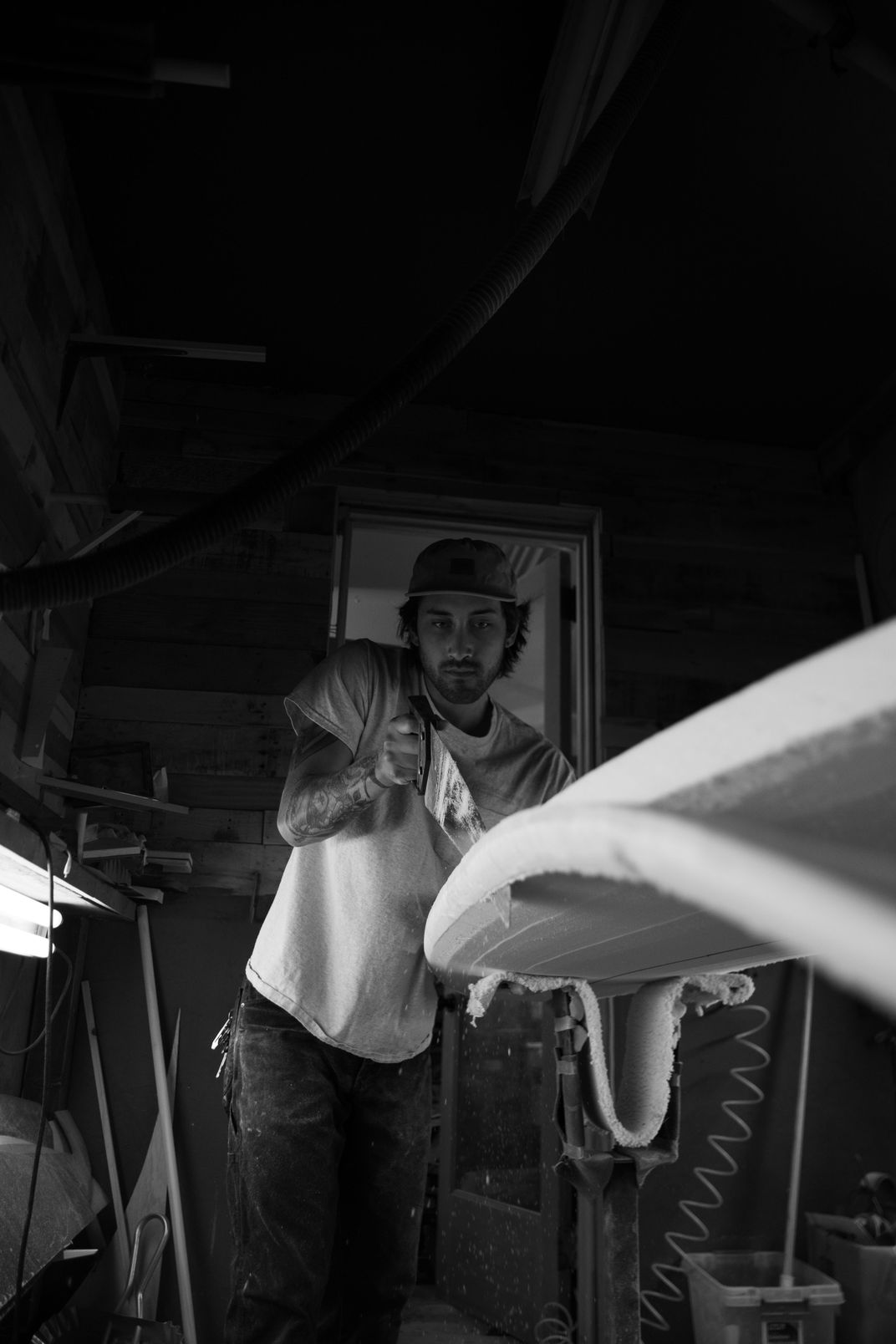 Joseph Yee, sawing foam in the process of shaping a surfboard ...
