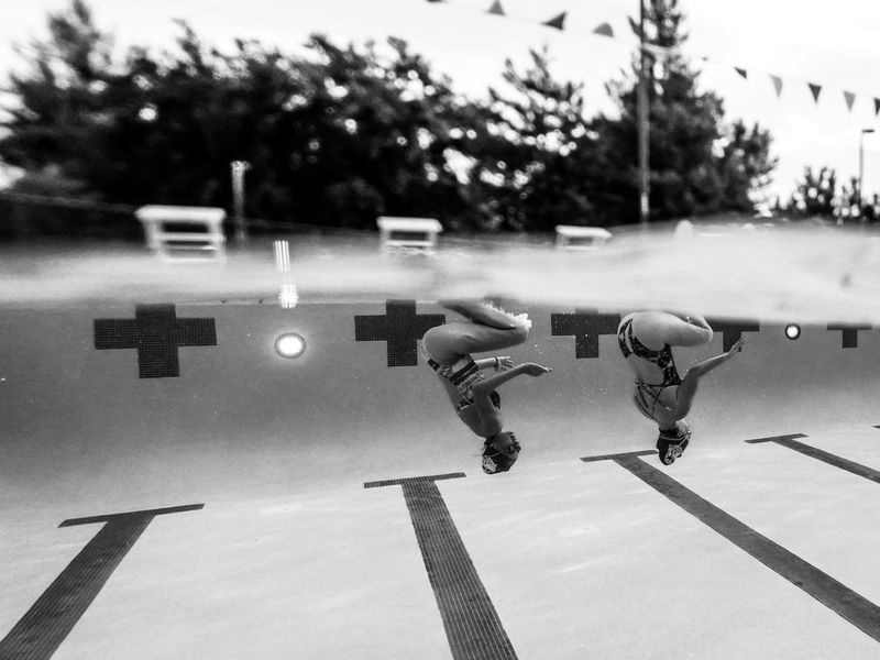 A split shot of a synchronized swimming duet performing a practice ...