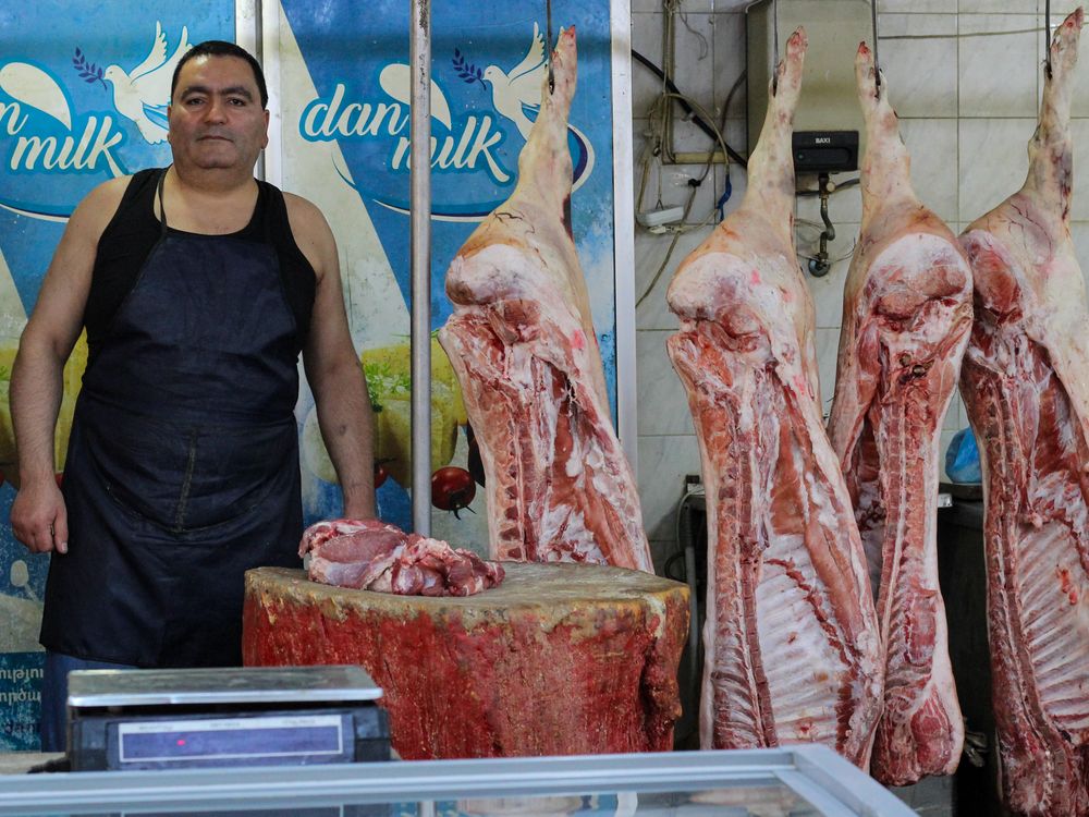 A butcher poses with meat carcasses at Tashir Bazaar in Yerevan ...