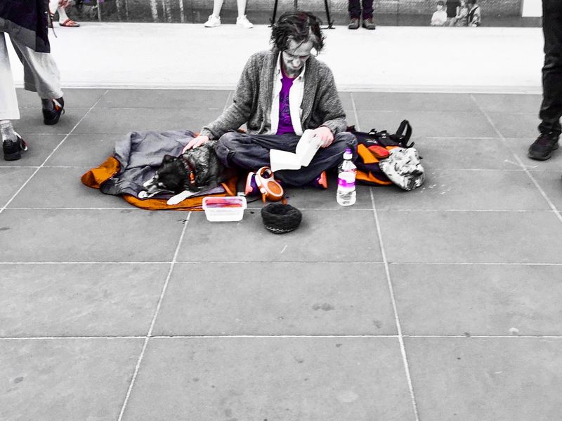 A Homeless man reading a book in the middle of a busy lane ...