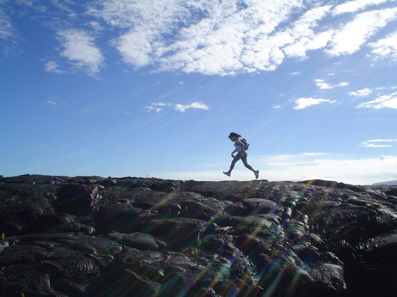 Young girl jumping across hardened lava in Hawaii Volcanoes National ...
