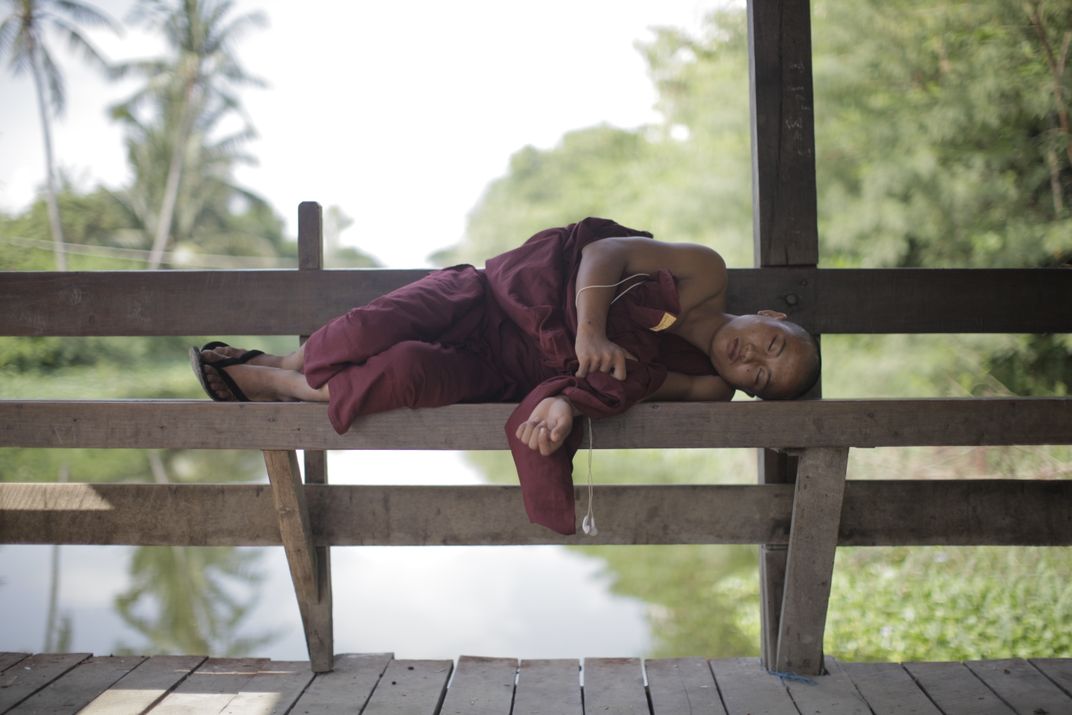 A young monk sleeps on a bridge over a canal in Myanmar. | Smithsonian ...