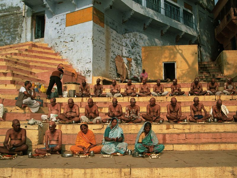 A ritual on the ghat of Varanasi, India where a group of Brahmins are ...