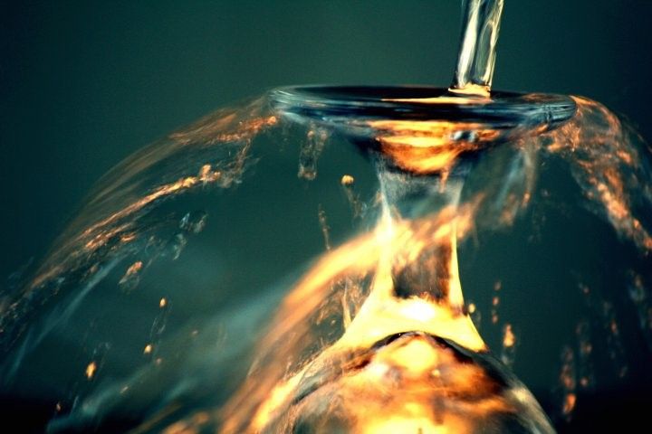Pouring water over the bottom of a glass with light shining through ...