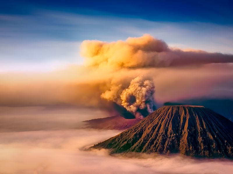 An active volcano was erupting while the sun is just about to rise and ...