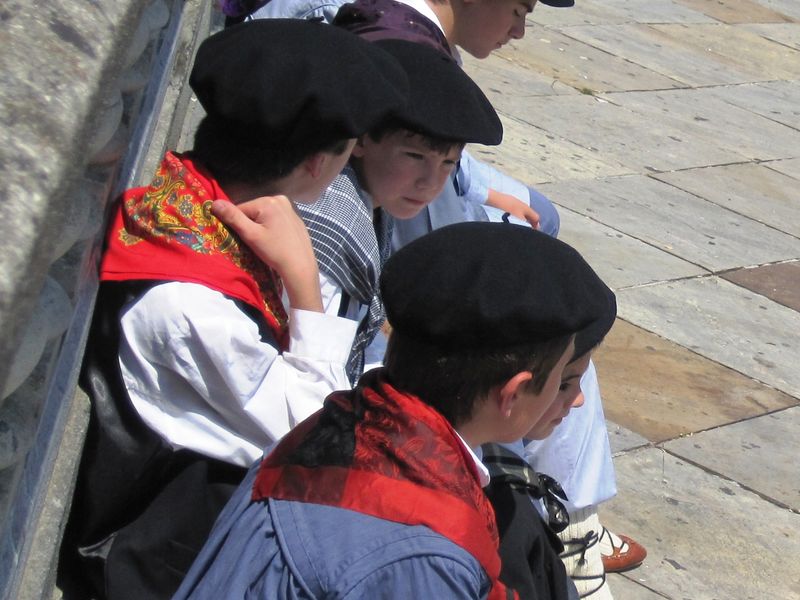 A group of Basque boys sit and wait in their traditional town attire ...