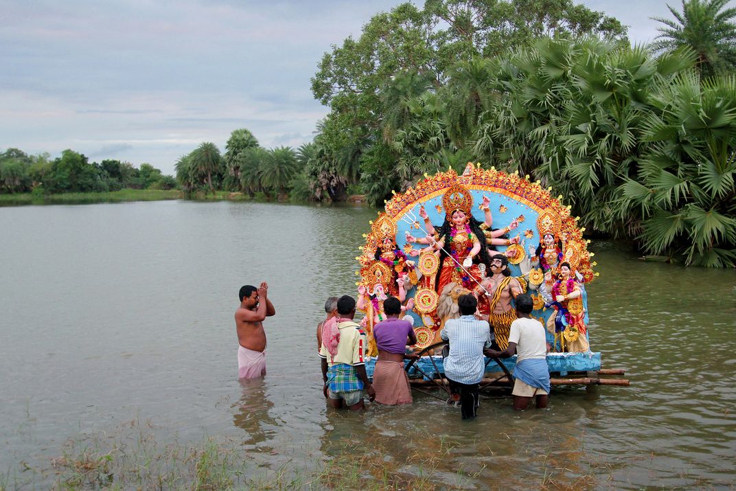 An idol of goddess 'Durga' is being immersed in a pond after her ...