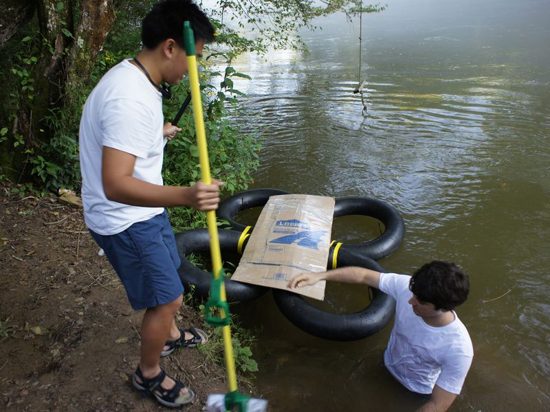 Two young men about to launch a home made raft of card board, tire ...
