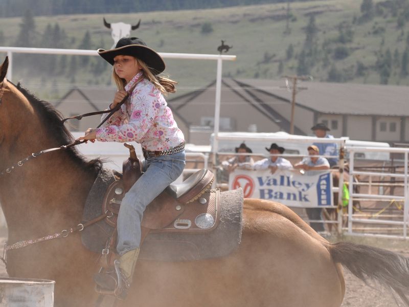 Young barrel racer carefully rounds first barrel during a Montana rodeo ...