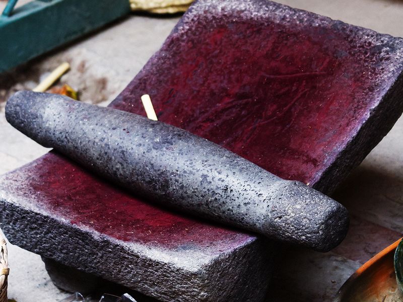 A basalt metate shows the color created by a weaver's pigment grinding ...