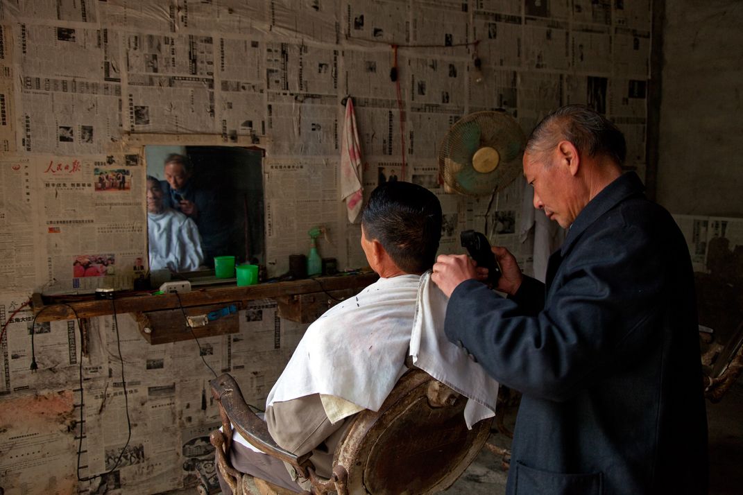 A practised village barber is doing haircut for a man. This kind of ...
