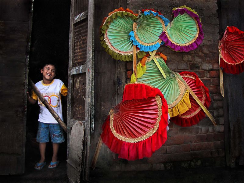 A boy with a bunch of typical Indian colorful hand-held fan. Taken with ...