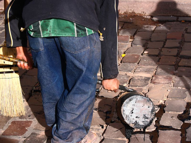 Worker pouring tar between bricks on a street in Quito | Smithsonian ...