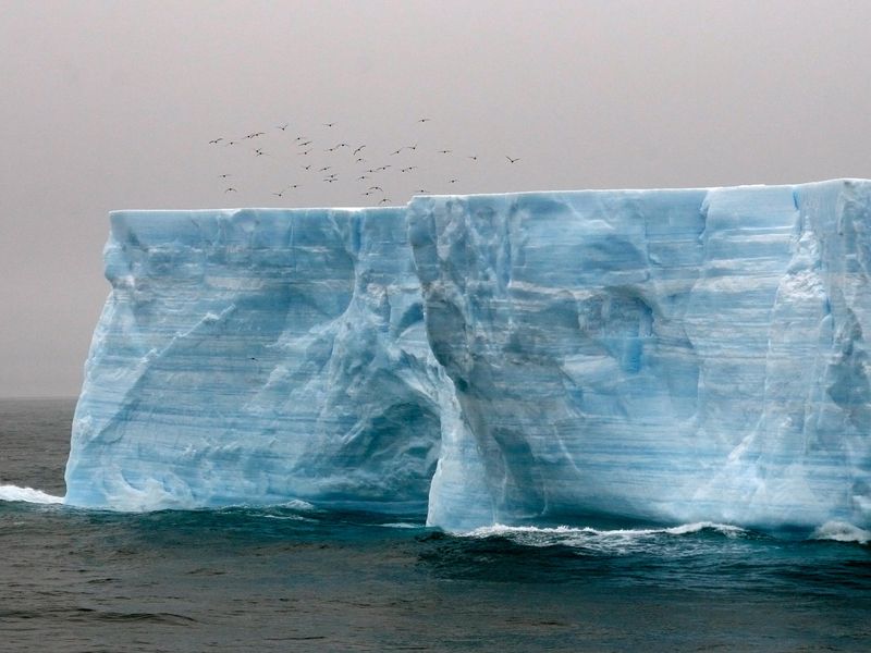 A tabular iceberg with distinct striations in Antarctic waters, with a ...