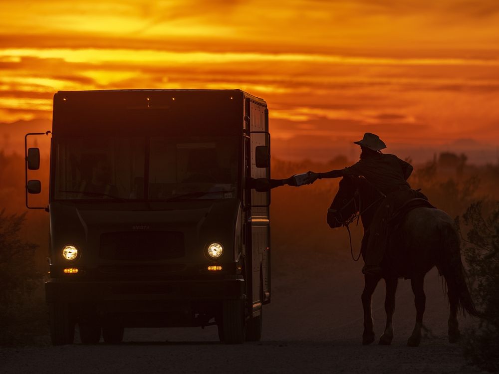 A cowboy accepts a package from a delivery driver on an Arizona ranch ...